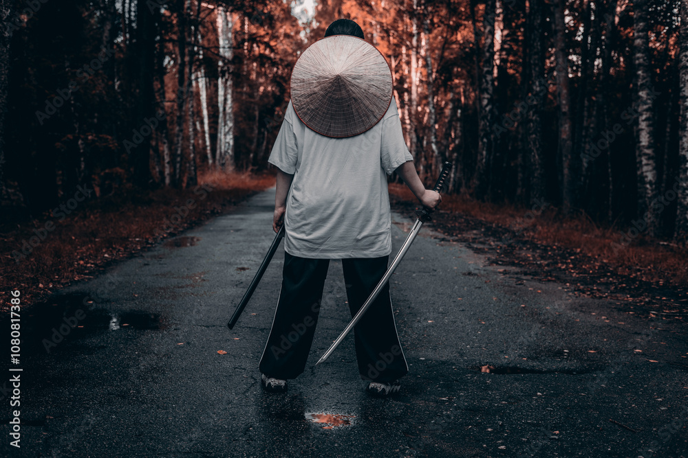 A samurai warrior wearing a straw hat stands on a path in the forest ...