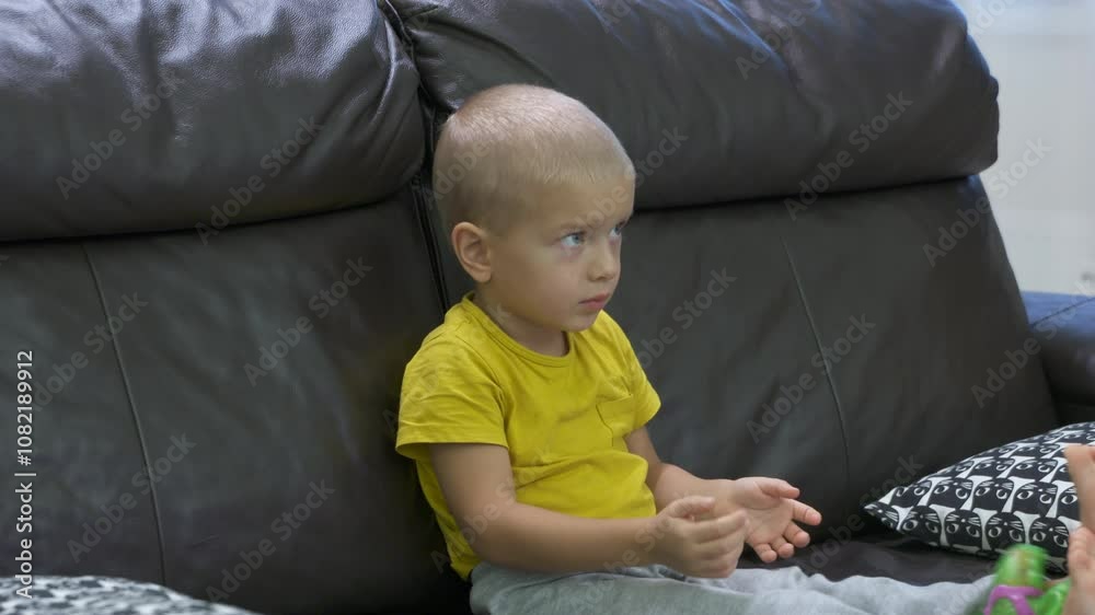 Child sitting on couch at home. Little boy looking attentively at TV ...