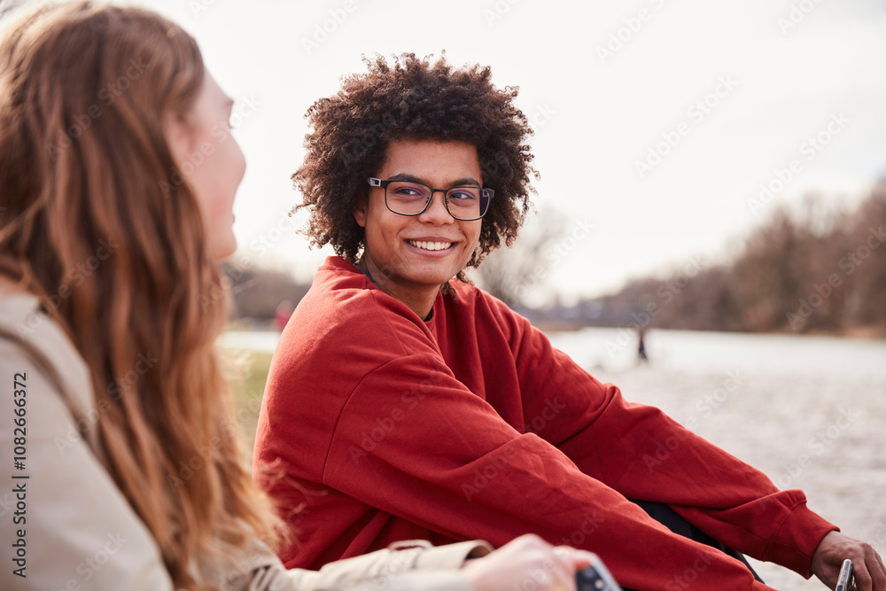 Gen Z couple outside beside a river hanging out and having fun together ...
