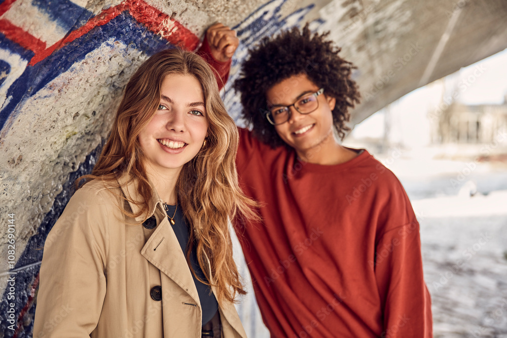 Gen Z couple outside under a bridge smiling at the camera. Munich ...