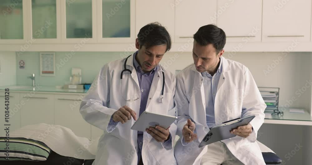 Two Latino surgeons review diagnose, lab results on patient medical ...