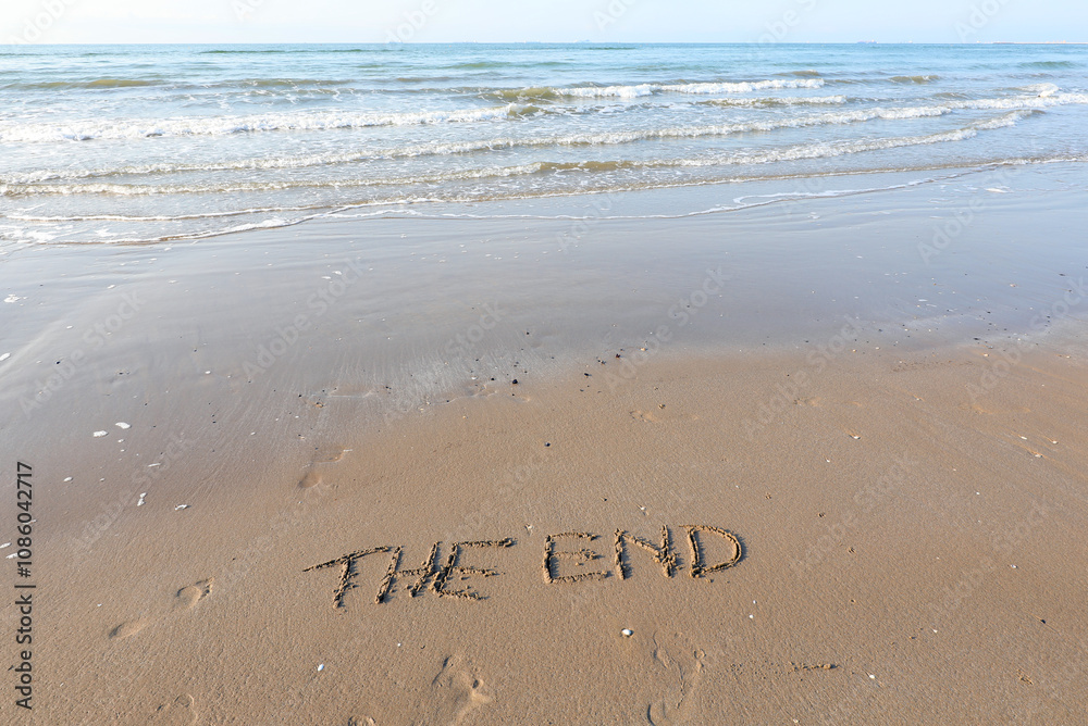 text THE END are written in the sand on a beach and an ocean wave is ...