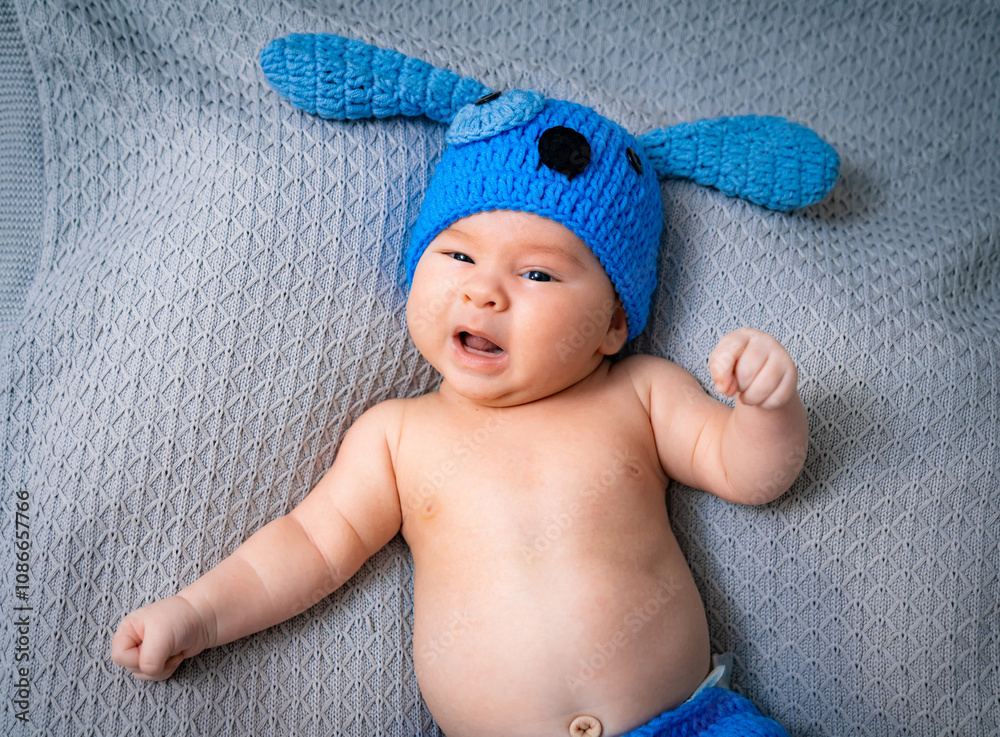Baby wearing blue bunny hat enjoys playful moment. A cheerful baby with ...