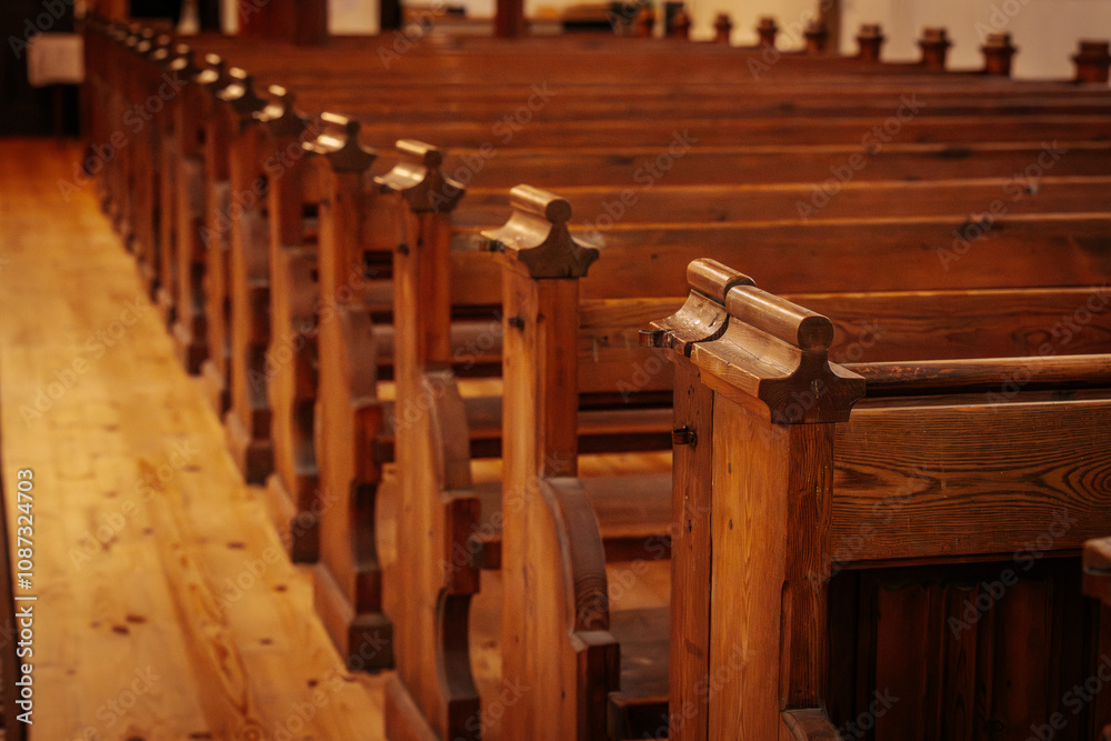 Rows of beautifully crafted wooden pews inside a church, illuminated by ...