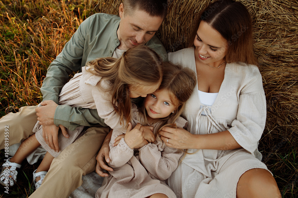 Happy family of four sitting on the field. Father, mother and two ...