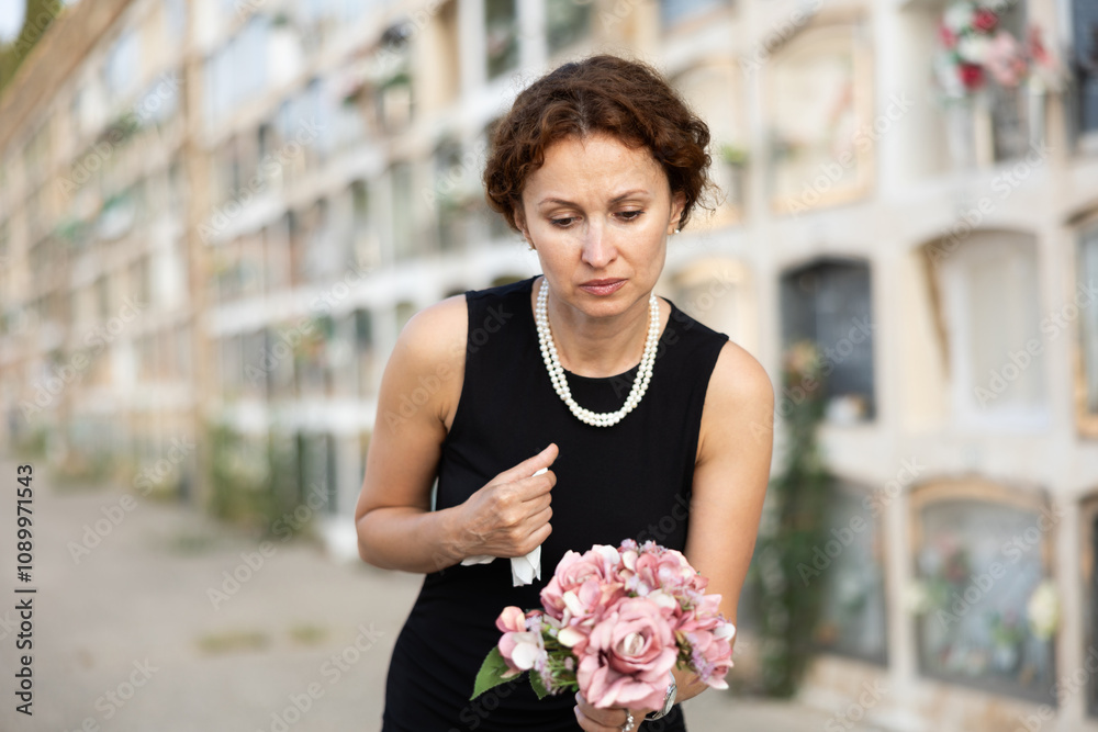 During visit to cemetery, woman in mourning clothes grieves for ...