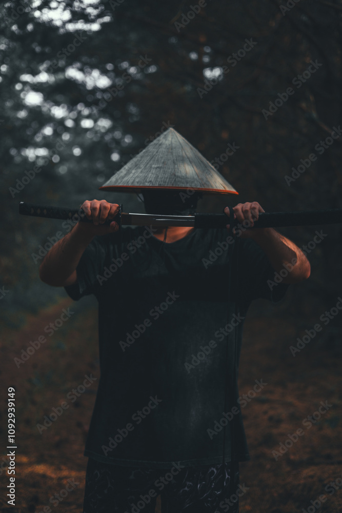 A warrior wearing a straw hat and a black mask stands in a fighting ...