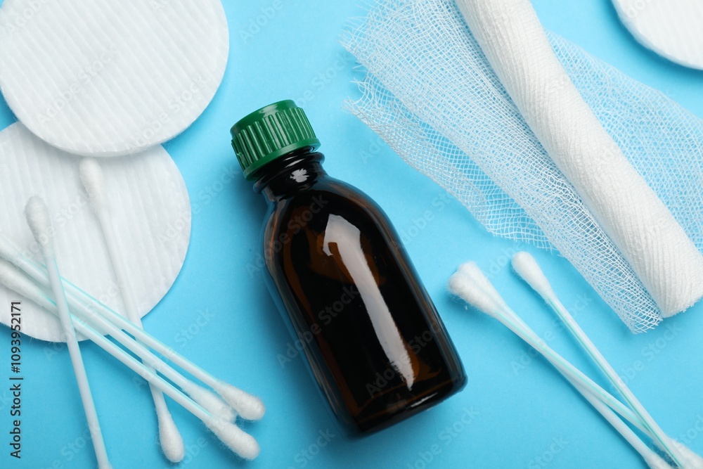 Topical iodine, bandage, cotton pads and swabs on light blue background ...