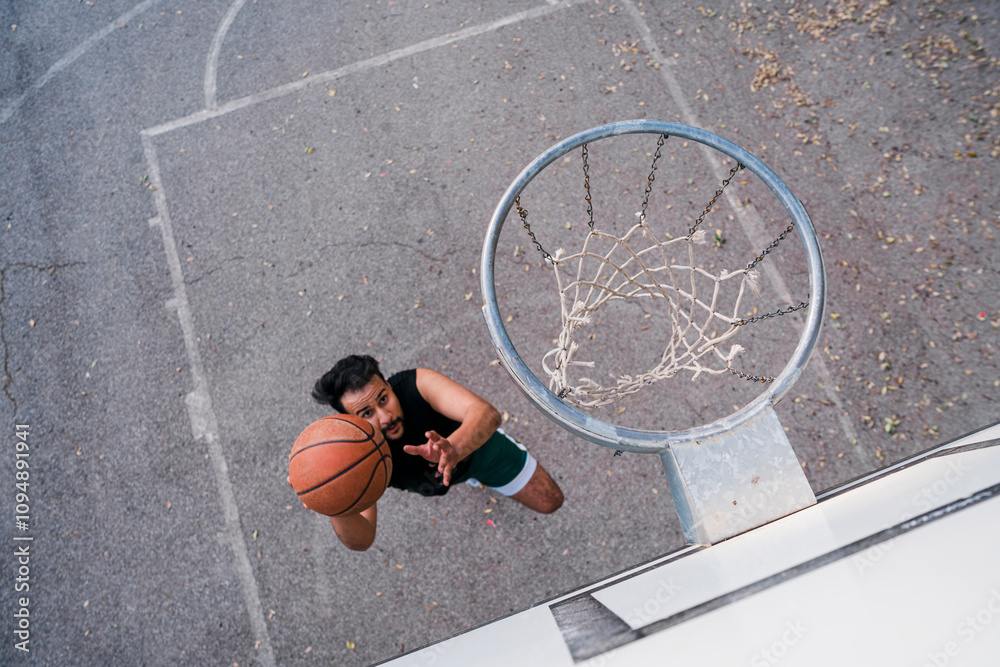 A top-down view of a basketball player in mid-air attempting a layup ...