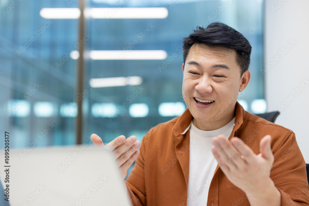 Asian man businessman engaged in video call in office. He appears happy ...