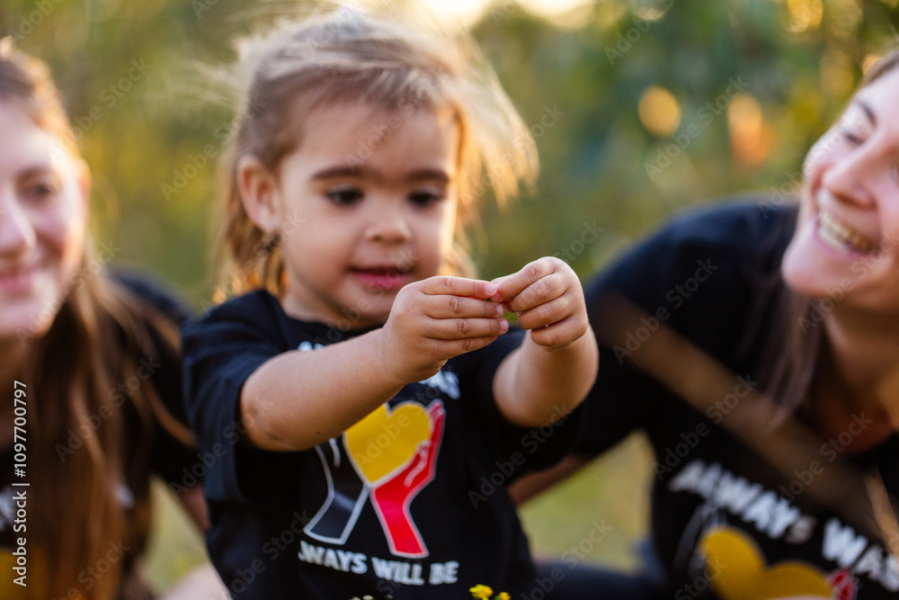 Aboriginal toddler playing outside in nature with big sister and mum ...