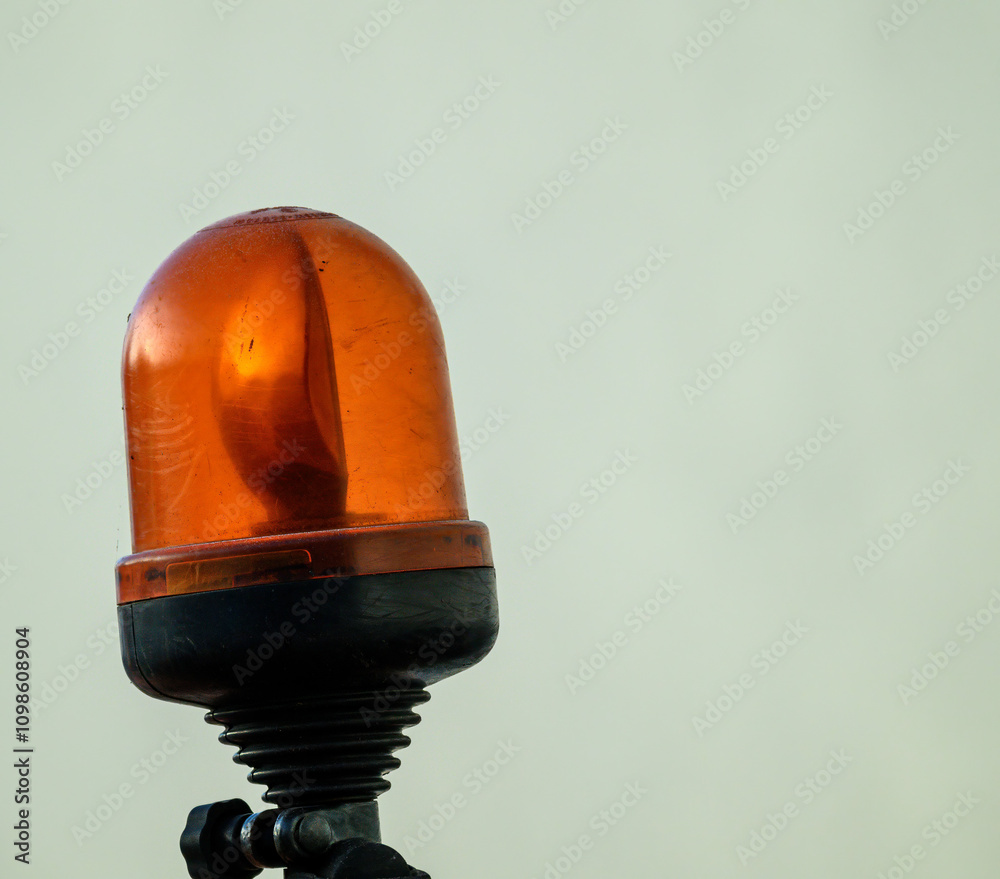 An orange rotating signal light is mounted on a sturdy base. The light ...