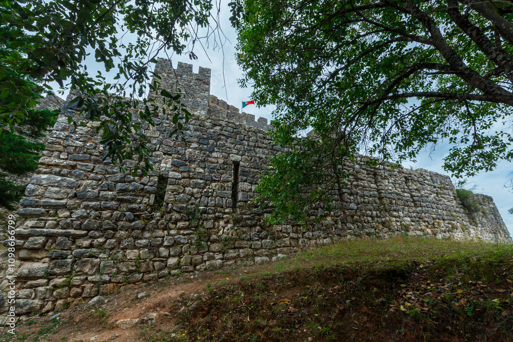 A towering medieval stone wall with a narrow slit window, surrounded by ...