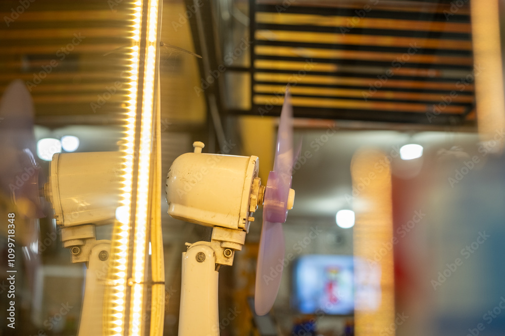 A wall-mounted fan in an Indonesian restaurant, providing cooling in a ...