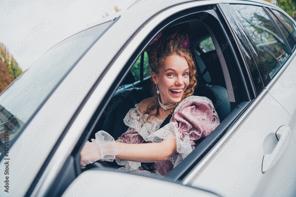 Joyful young woman in vintage dress driving a modern car combines ...