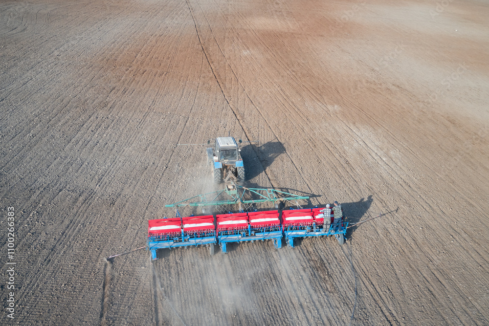 Sowing campaign. Tractor with trailed seeder working in the field ...