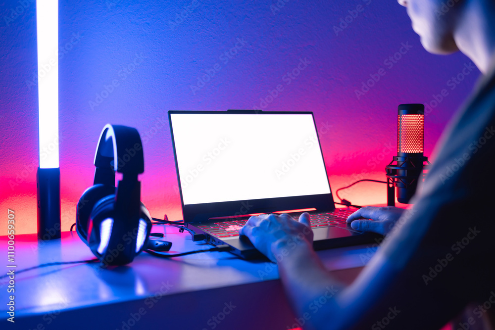 Gamer using a gaming laptop with a blank screen in a colorful LED-lit ...