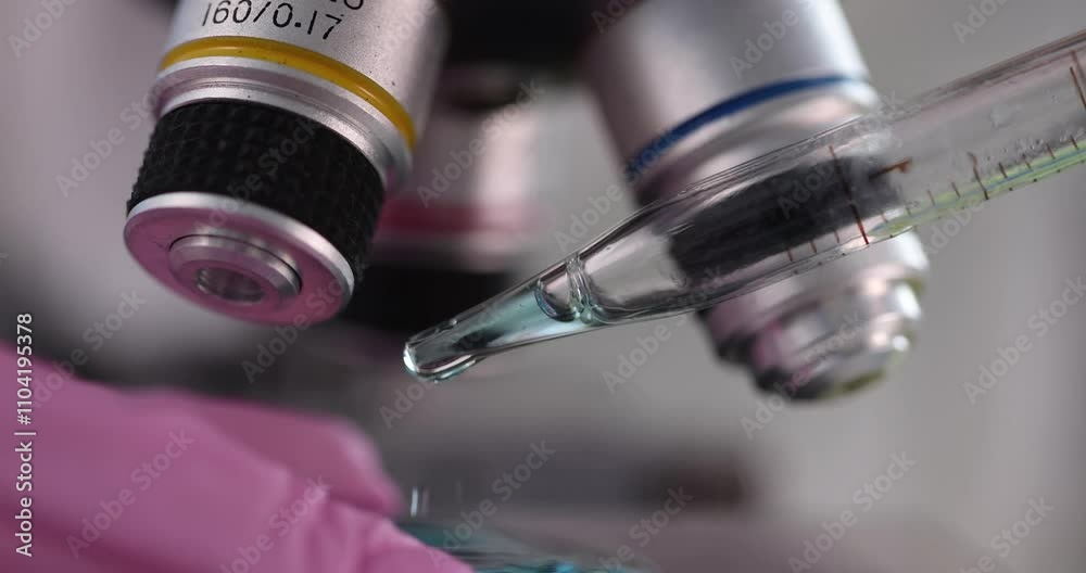 Lab technician pours liquid onto micro specimen for examination ...