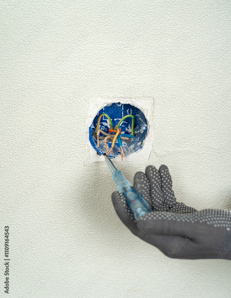 Hands of electrician check current in open junction box with electrical ...
