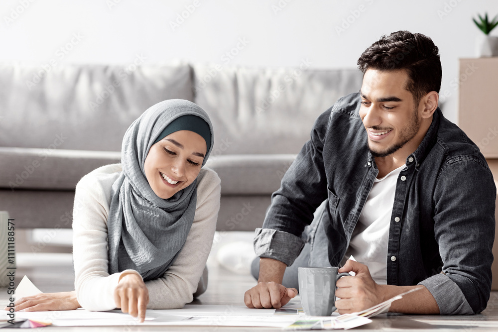 Excited young muslim family husband and wife in hijab laying on floor ...