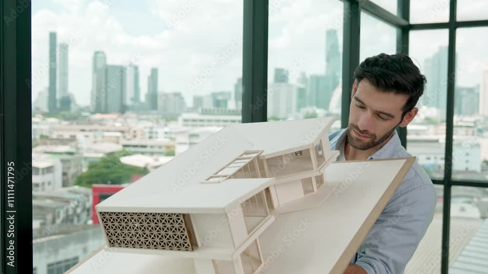 Skilled smiling caucasian engineer turns house model left and right to ...
