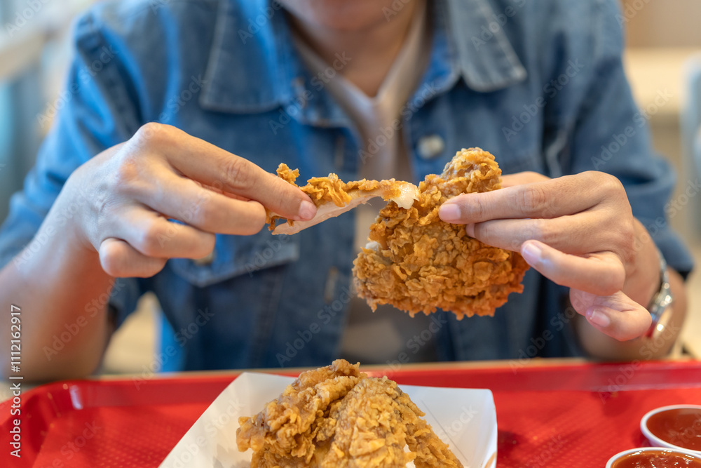 Close-up of a young woman's hand tearing a large piece of fried chicken ...