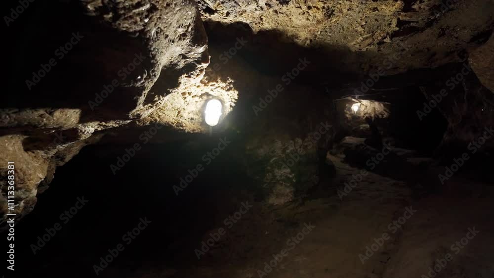 Shooting in an underground cave illuminated by lamps. Exploring a stone ...