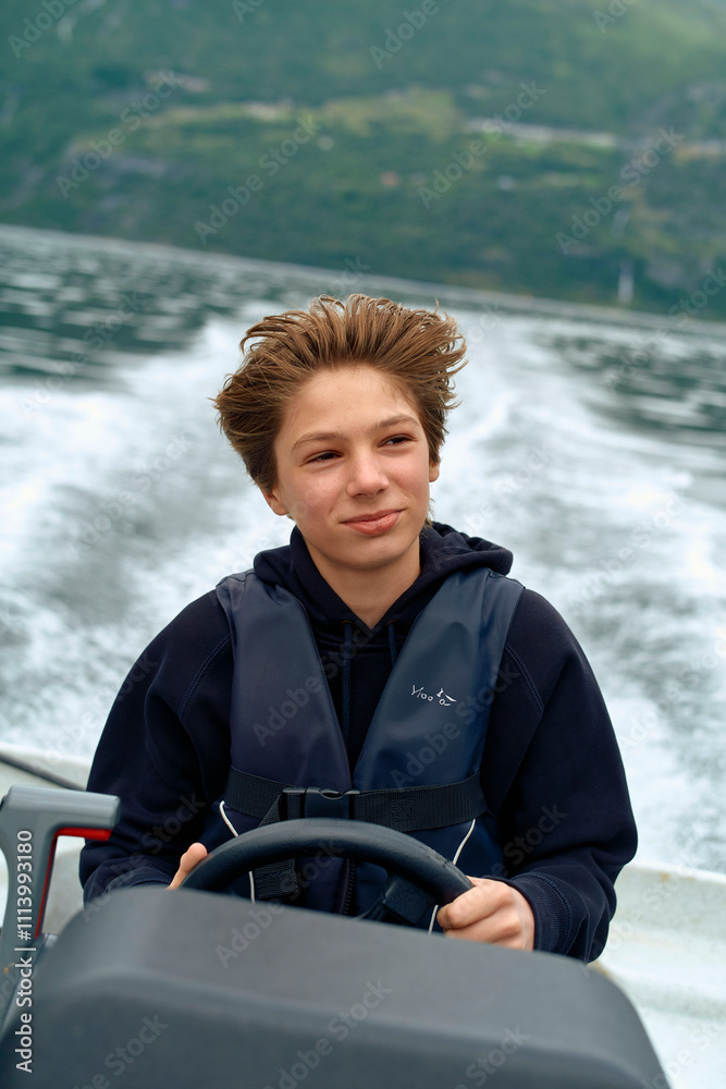 Confident teenager steering a boat with water churned up in the ...