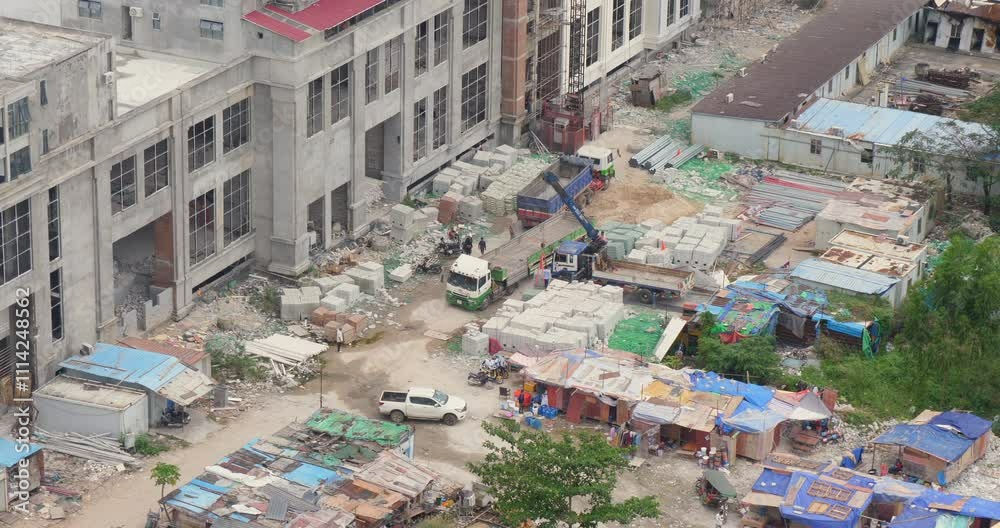 construction site with trucks and a crane lifting materials.The area is ...