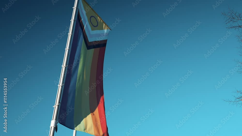 New Progress Pride Flag waving proudly outdoors on a pole, symbolizing inclusivity and diversity ...