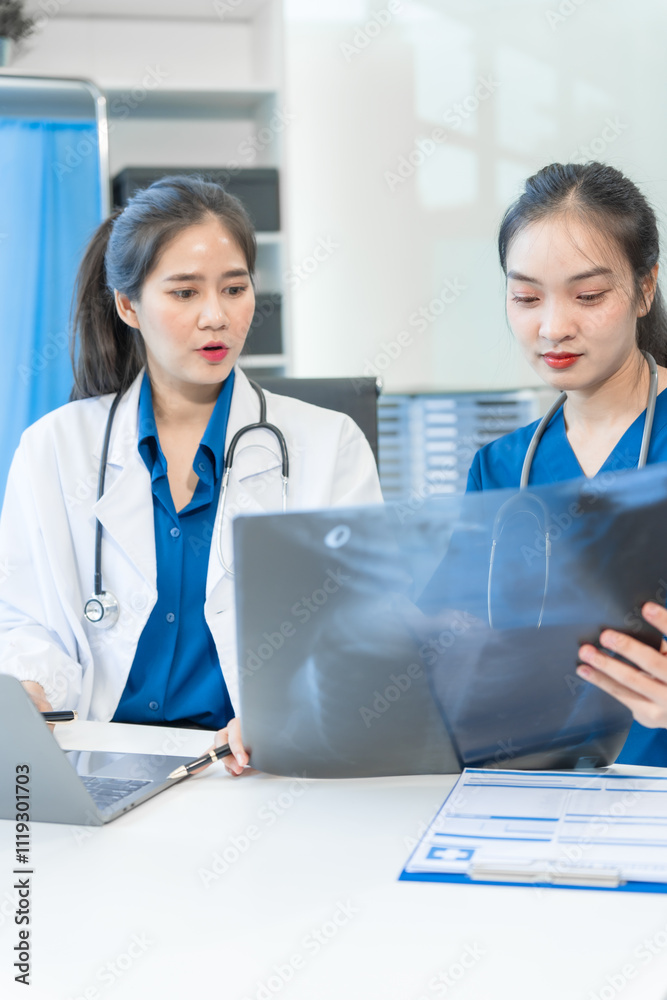 Two young female doctors sit at a table, discussing a patient's blood ...