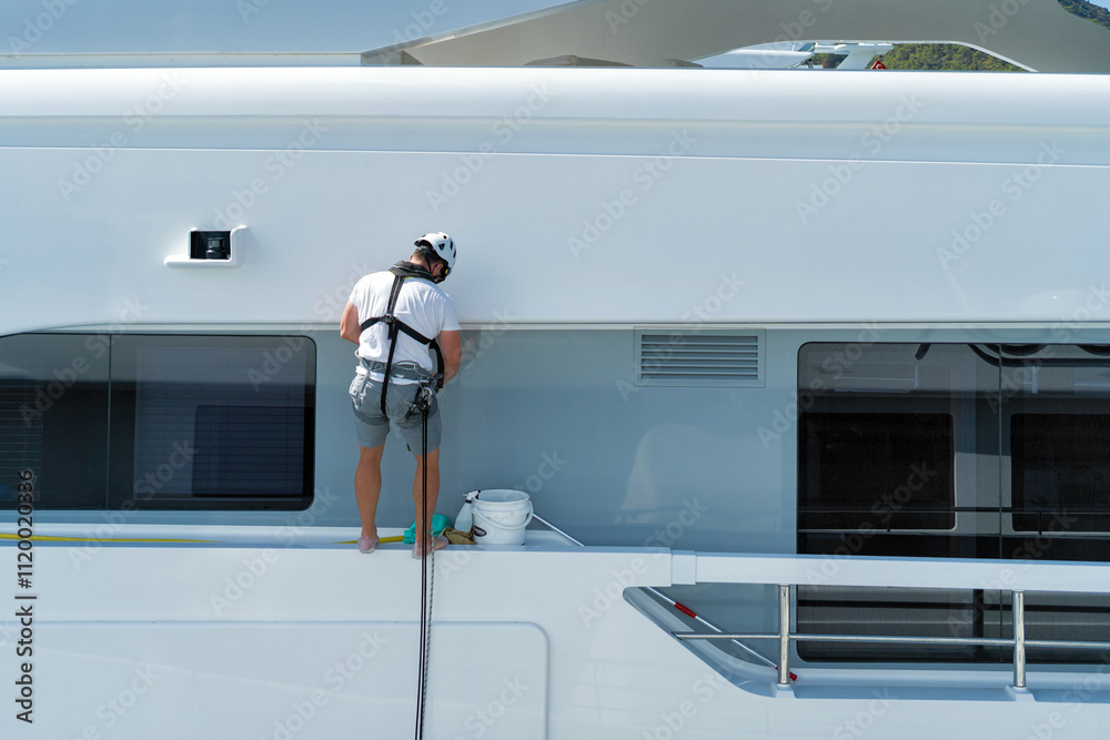Male Caucasian Deckhand working on the side of a white modern ...