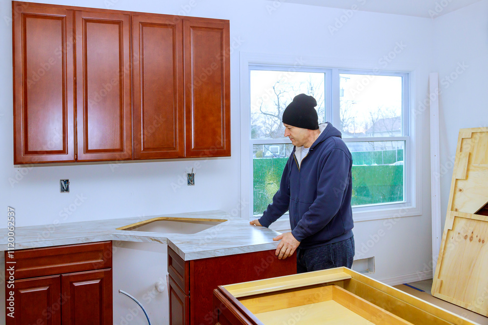 Contractor is carefully placing countertop in newly renovated kitchen ...