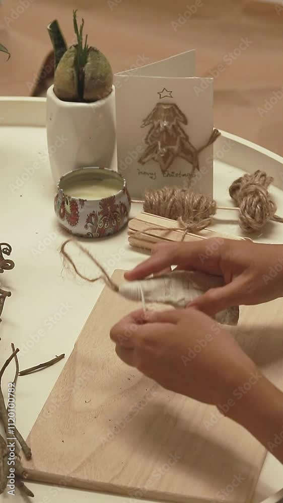 Wrapping white yarn around a triangle paper mold on a craft table with ...