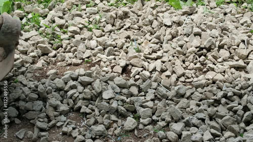Close Up shot footage of a hoe leveling split stones to cover the yard ...