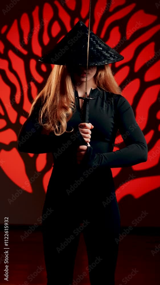 A woman in a black suit and sugegasa with a samurai sword poses against ...