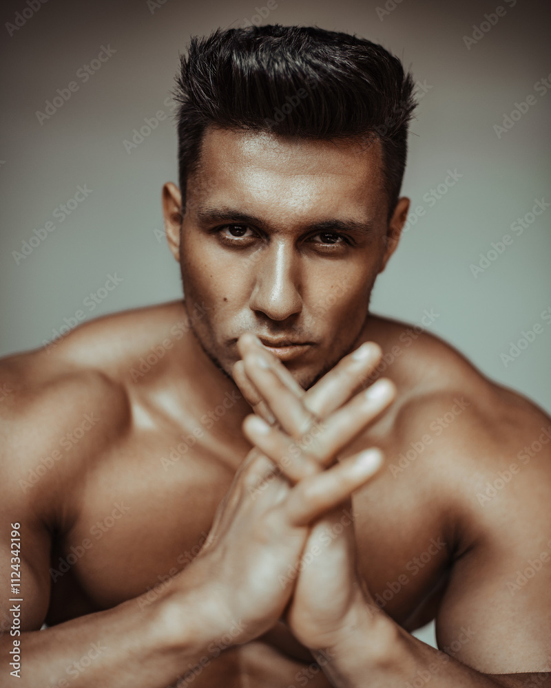 Tanned muscular brunette looks straight into the camera with seductive look. Male model poses in ...