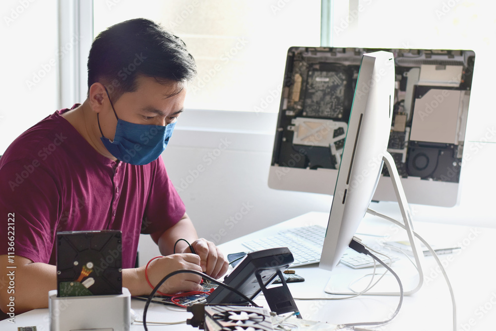 computer technician wearing a mask A motherboard repairman is using an ...