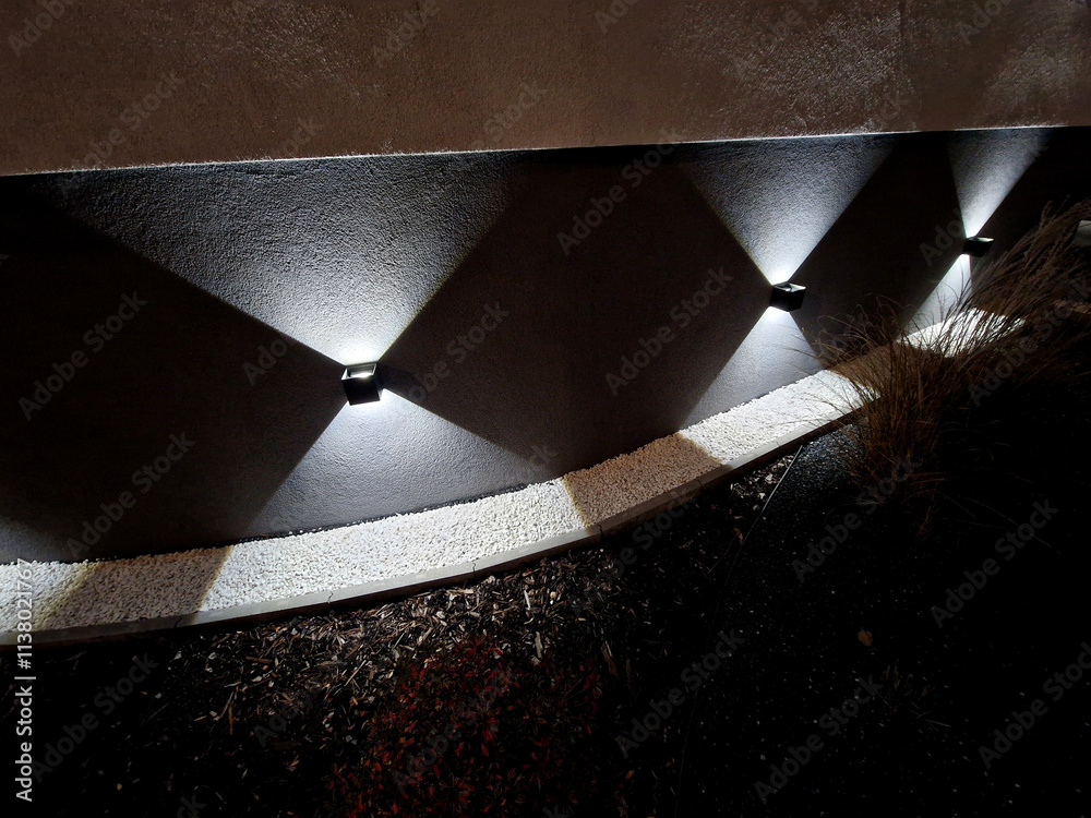 spot wall light illuminates the wall of facade of the house in a ...