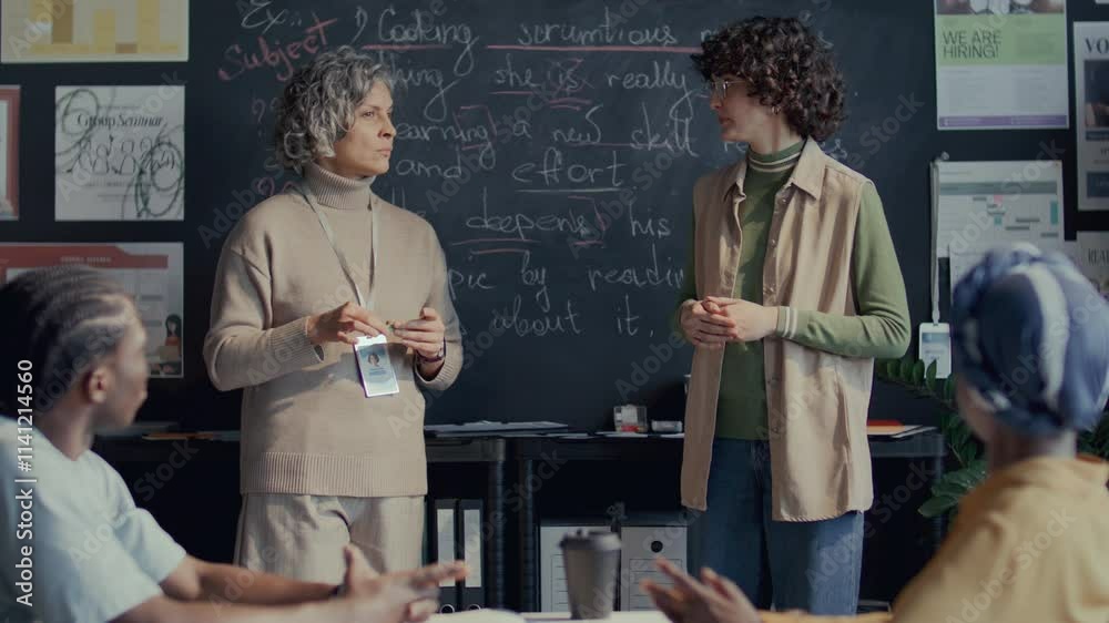 Young Caucasian girl standing at blackboard with mature female teacher ...