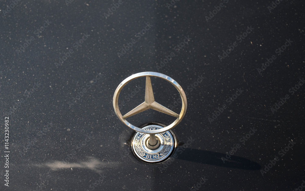 Close-up view of Mercedes Benz car emblem on a sleek black surface ...