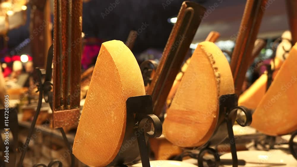 Raclette cheese wheels melt on grills at a traditional food market ...