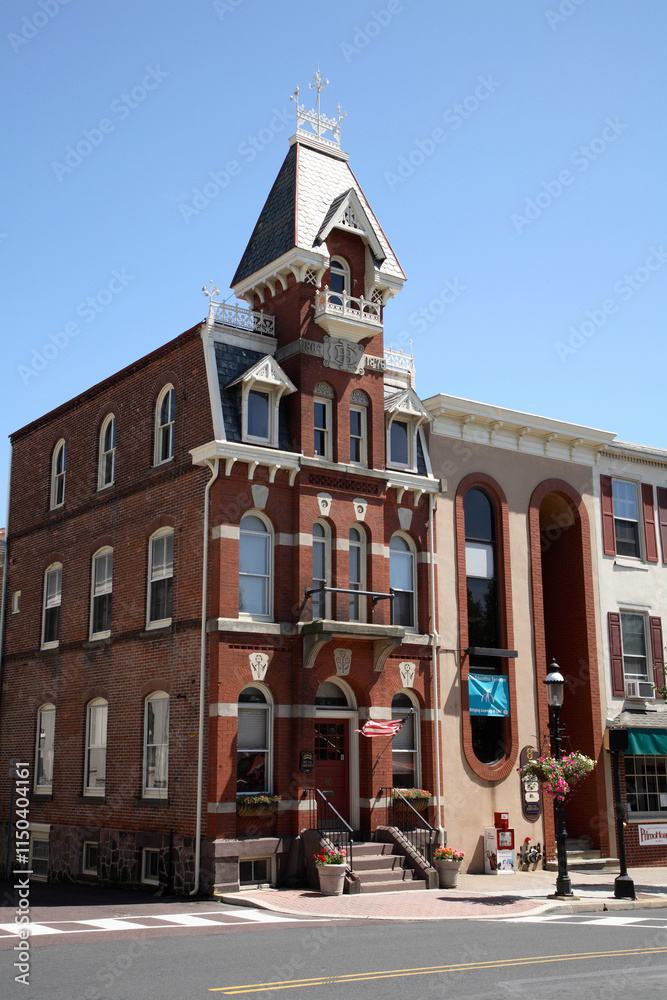 Narrow three story brick building with tall arched windows and small ...