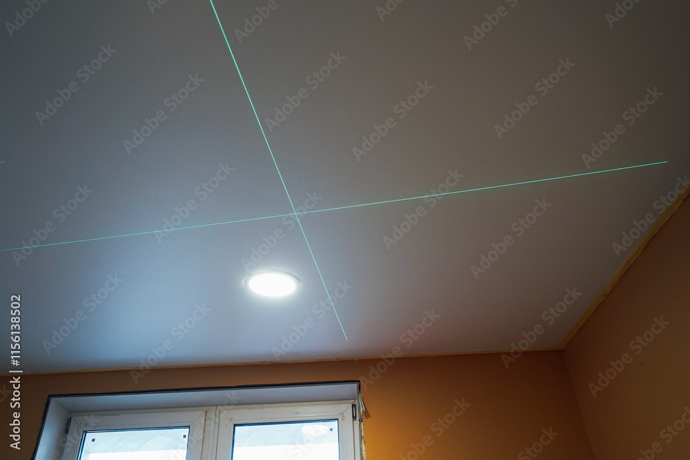 Bright green lines, perfectly aligned on the ceiling, guide construction workers in creating ...