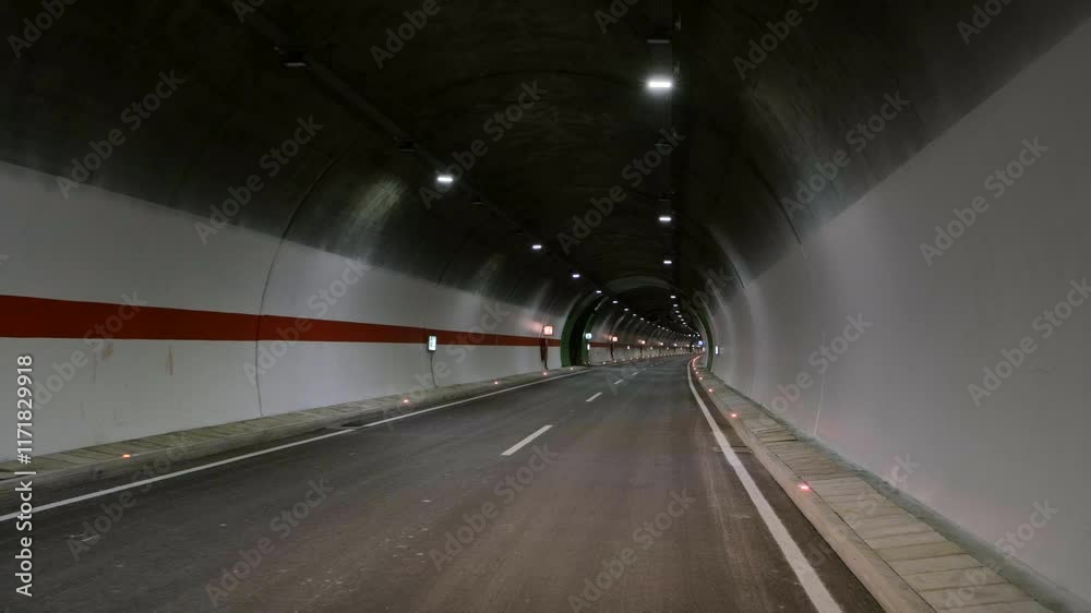 The image shows a highway inside a tunnel. The road is smooth, well-lit ...