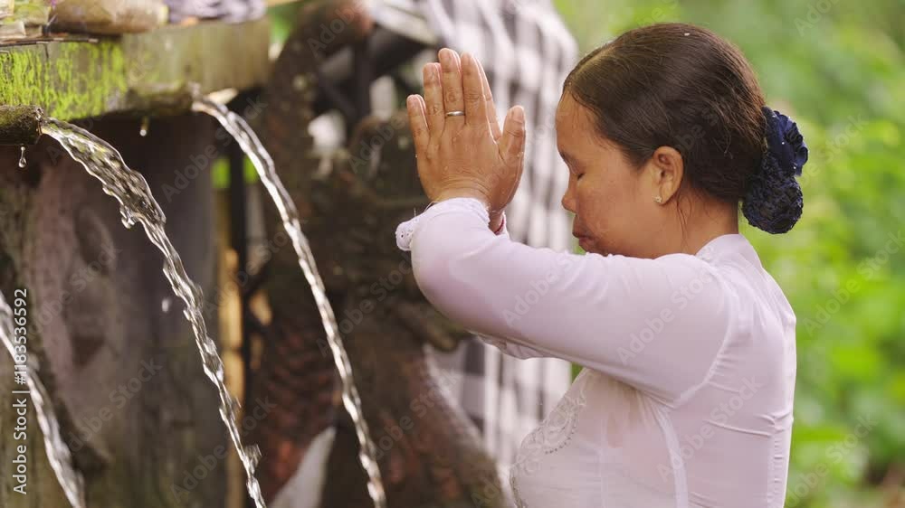 Balinese woman praying with hands in ceremony at temple, water ...