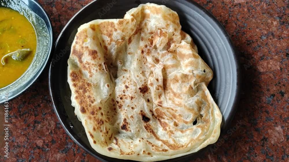 A serving of roti canai, a popular Malaysian dish, placed on a table ...