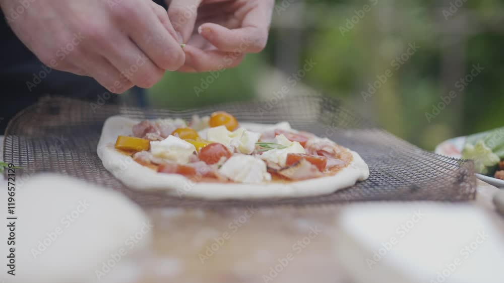 A person is making a pizza with tomatoes and cheese. The pizza is on a ...