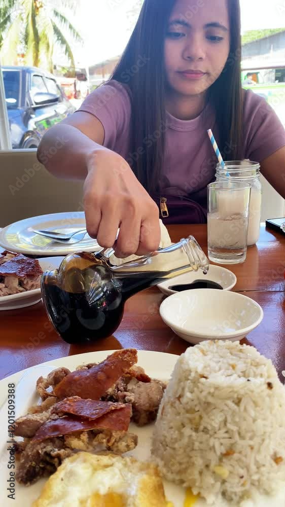 young Filipina woman in a Filipino traditional food restaurant pours ...