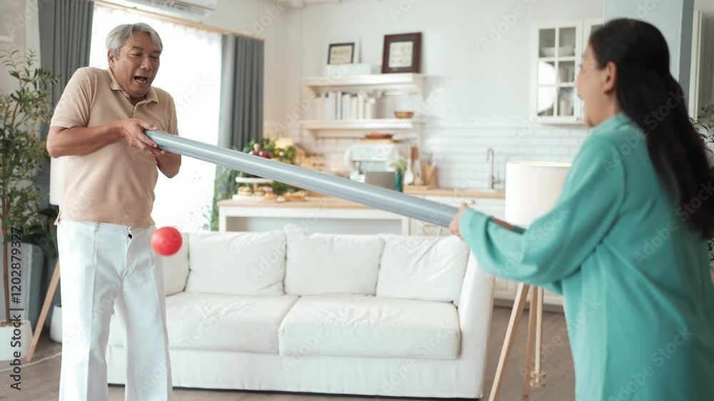 Elderly man playing a ball rolling game with his partner at home, practicing hand-eye ...